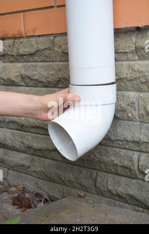 A clogged gutter of a plastic drainage pipe on the street coming out of ...