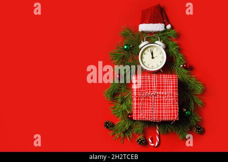 Alarm clock in a santa hat against the background of a christmas tree ...