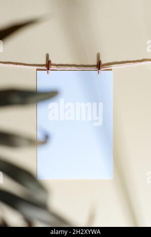 Blank paper card attached pegs hans on a rope with leaf Stock Photo - Alamy