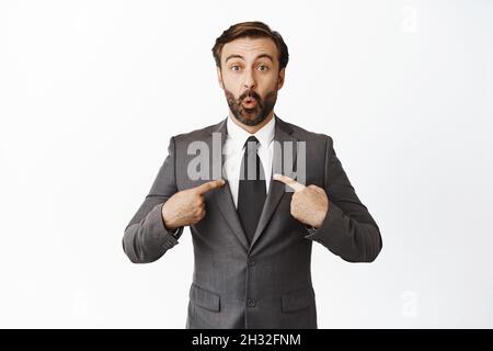 Surprised salesman in suit, pointing finger left at empty space ...