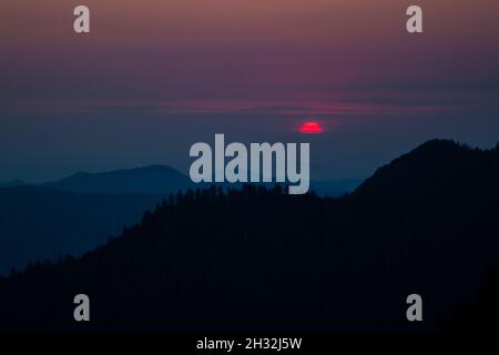 Colorful sunset over mountains overgrown with forest, Orange sun going ...
