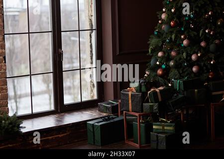 Big Christmas tree with presents near brick wall in room Stock Photo ...