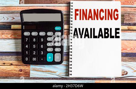FINANCING AVAILABLE, text on white notepad, near calculator on wooden ...