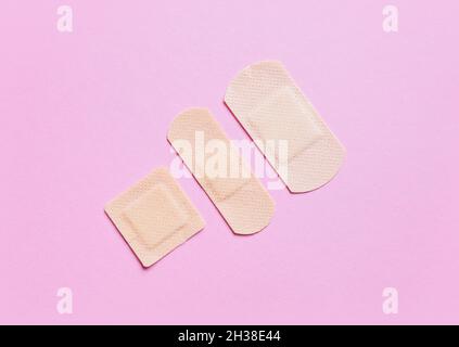 Different medical plasters on pink background Stock Photo - Alamy