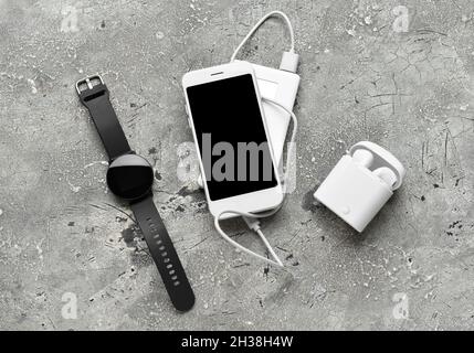 Modern power bank, smartwatch and mobile phone on green background ...