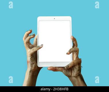 Hands of zombie with tablet computer on dark background. Happy ...