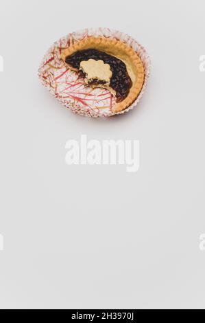 nibbled cherry jam pie in a paper backing cup on a white background ...