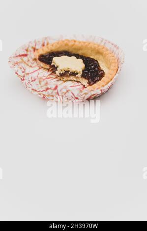 nibbled cherry jam pie in a paper backing cup on a white background ...