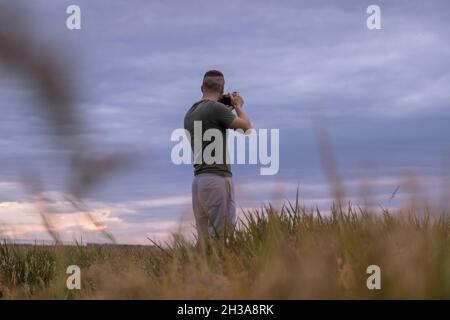 Hispanic man taking pictures of the beautiful grassy field on a cloudy ...