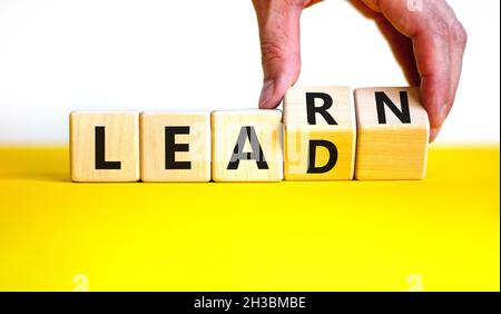 Learn and lead symbol. Businessman turns a wooden cube and changes the ...