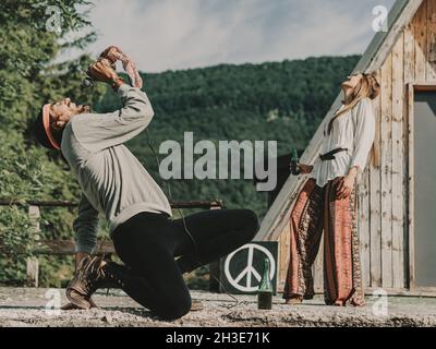 Hippie couple singing and drinking alcohol drinks while resting ...