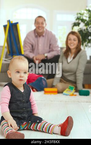 Beautiful toddler sitting on the floor playing with small colorful ...