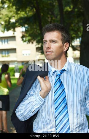 confident businessman in formal wear standing with hands in pockets ...