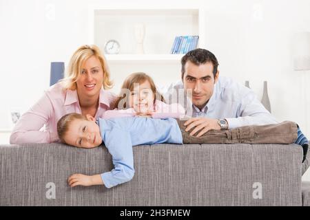 Portrait of loving young family of four on small bridge in the park ...