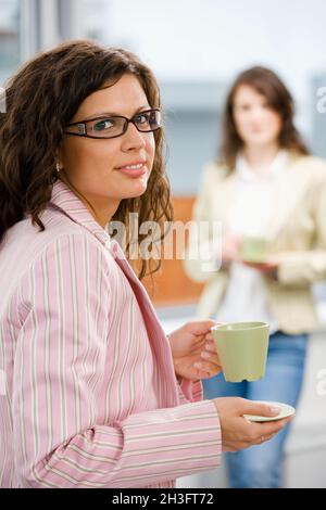 Portrait of two professionals in a coffee shop, sharing a smile during ...