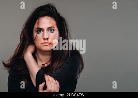 a battered woman in black clothes on an isolated gray background ...