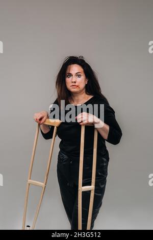 a battered woman in black clothes on an isolated gray background ...
