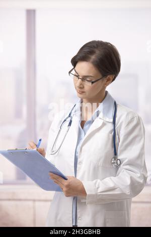 Female healthcare worker doing some paperwork and using laptop while ...