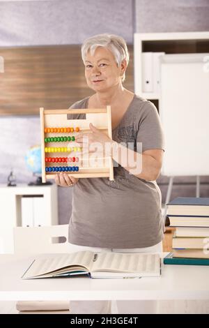 Mature female math teacher holding paper sheet with text BACK TO SCHOOL ...