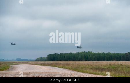Two blue and white helicopters landing in a grass field Stock Photo - Alamy