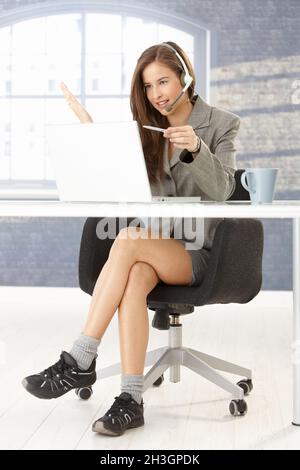 Image of bright call center. Focus on young blonde woman in a headset ...