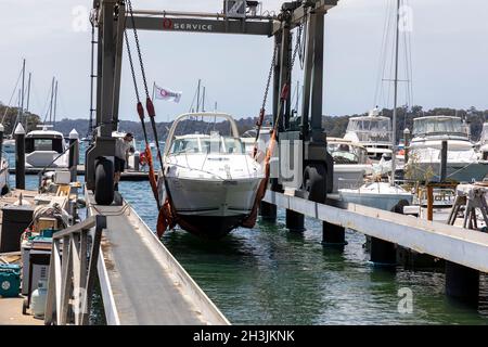Cruiser boat being lifted into the water from a marina lift hoist ...