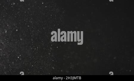 Dust particles float in neutral light on black background, wide photo ...