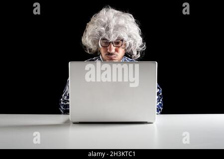 A boomer senior-focused concentrated sit at the desk looking at laptop ...
