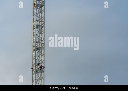 Two tower crane operators climb down the ladders high in the sky at the ...