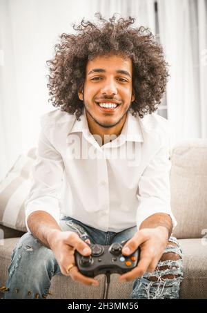 Young arab man playing video game sitting on sofa at home Stock Photo ...