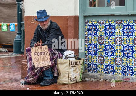 A middle-aged male begs holding his cardboard sign up in front of a ...
