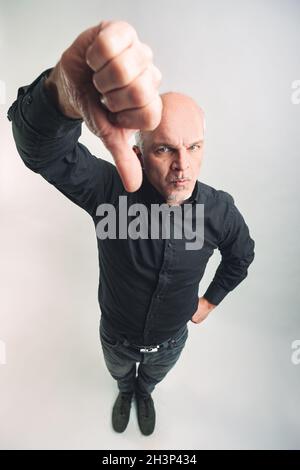 Unimpressed senior man giving a thumbs down gesture Stock Photo - Alamy