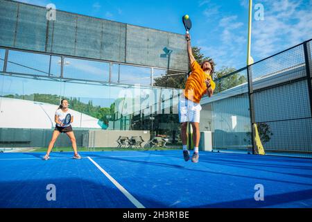 Mixed padel match in a blue grass padel court - Beautiful girl and ...
