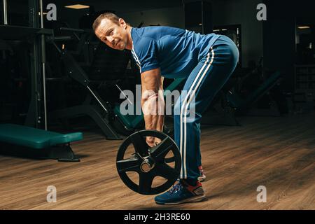 Fit elderly man lifting barbell in a gym Stock Photo - Alamy