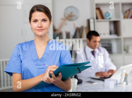 Positive nurse with folder of documents at office Stock Photo - Alamy