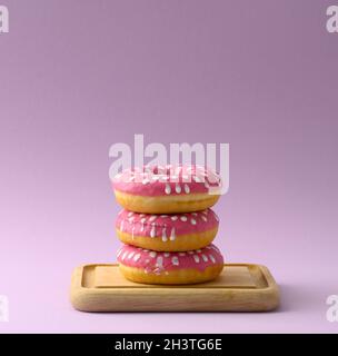 stack of pink donuts with icing on a yellow background, copy space ...