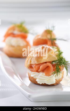 Profiteroles stuffed with cream cheese and salmon, decorated with a ...