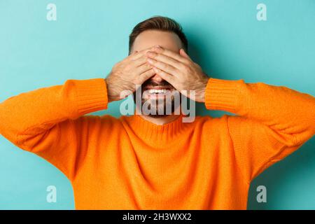 Happy smiling guy waiting for surprise, covering eyes with hands and ...