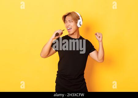 Carefree handsome asian guy, korean singer singing into microphone with ...