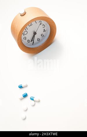 Alarm clock with pills on table in room Stock Photo - Alamy