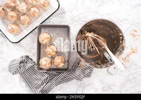 Flat lay. Scooping mixture into the small glass jars to make homemade ...