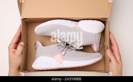 Cardboard box with white sneakers on green background Stock Photo - Alamy