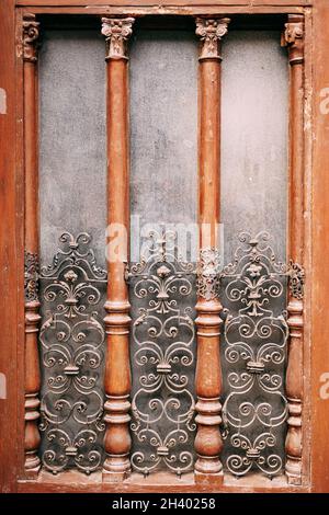A wooden window with a metal lattice with patterns up to the middle and ...