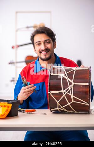 Young repairman repairing musical instruments at workplace Stock Photo ...