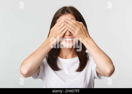 Excited girl waiting for surprise while eyes covered with hands ...