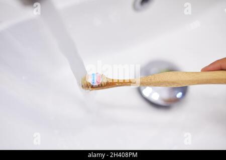 Ecologe wooden Toothbrush with toothpaste under water jet at home ...