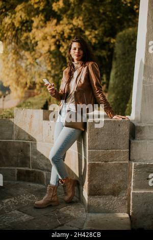 Pretty young woman using a mobile phone while walking on the street ...