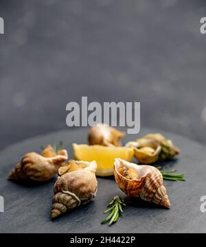 Snails with lemon on black platter Stock Photo - Alamy