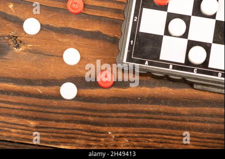 A board for playing checkers with chips on a wooden table, close-up ...