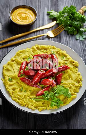 mashed green peas with fried deviled sausages on white plate on a white ...